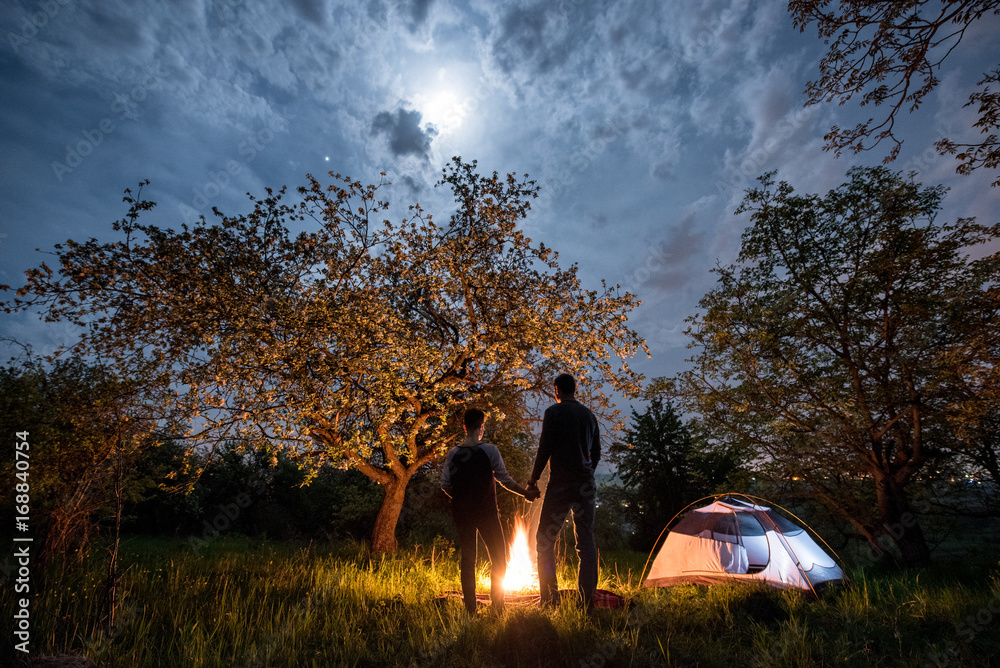 Foto de Rear view of romantic couple tourists standing at a campfire ...