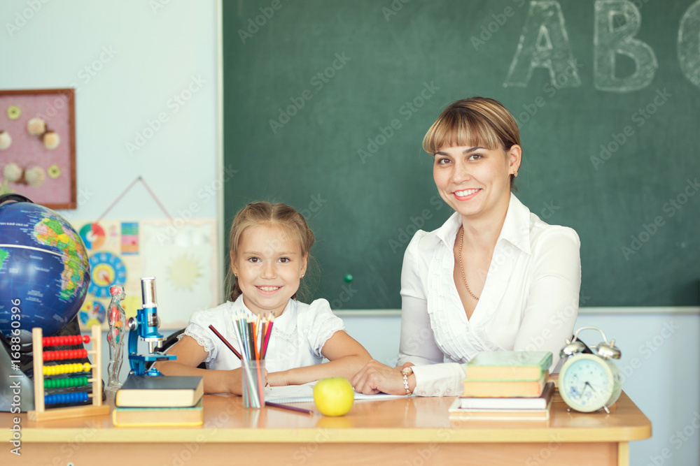 Cute schoolgirl and her teacher in a classroom Stock Photo | Adobe Stock