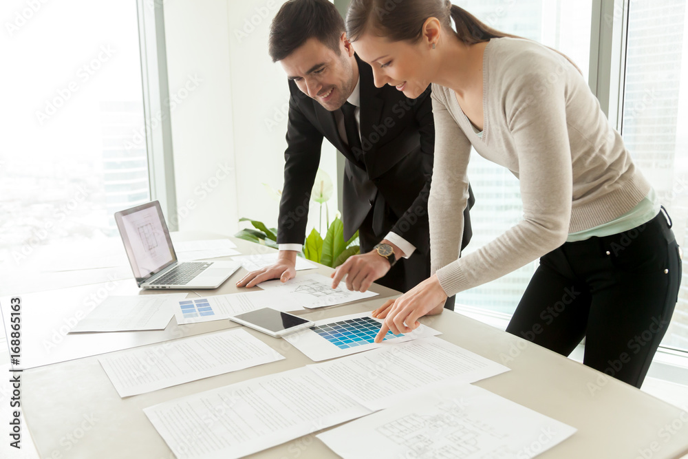 Smiling professional designers working on project at office desk ...