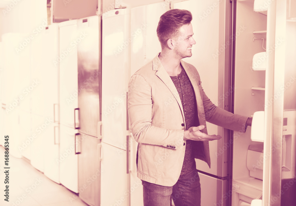 Happy young man selecting domestic refrigerator Stock Photo | Adobe Stock