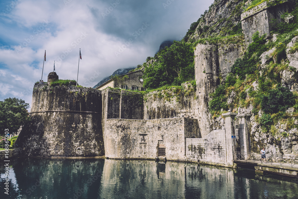 Kotor fortress wall and Old Town Stari Grad with cloudy mountains on ...