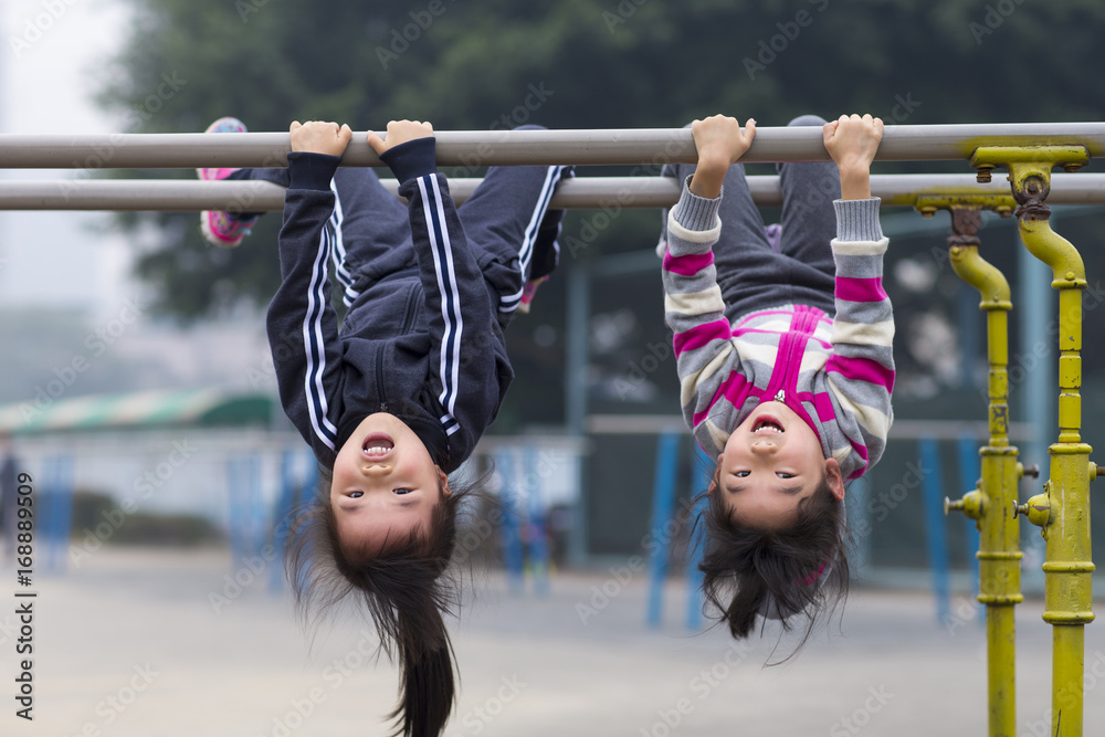 Lovely two Little GIrls hang on parallel bars Stock Photo | Adobe Stock
