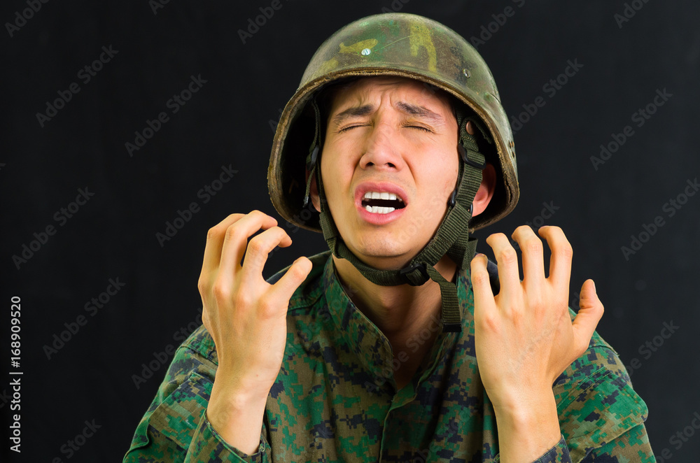 Handsome young soldier wearing uniform suffering from stress, screaming ...