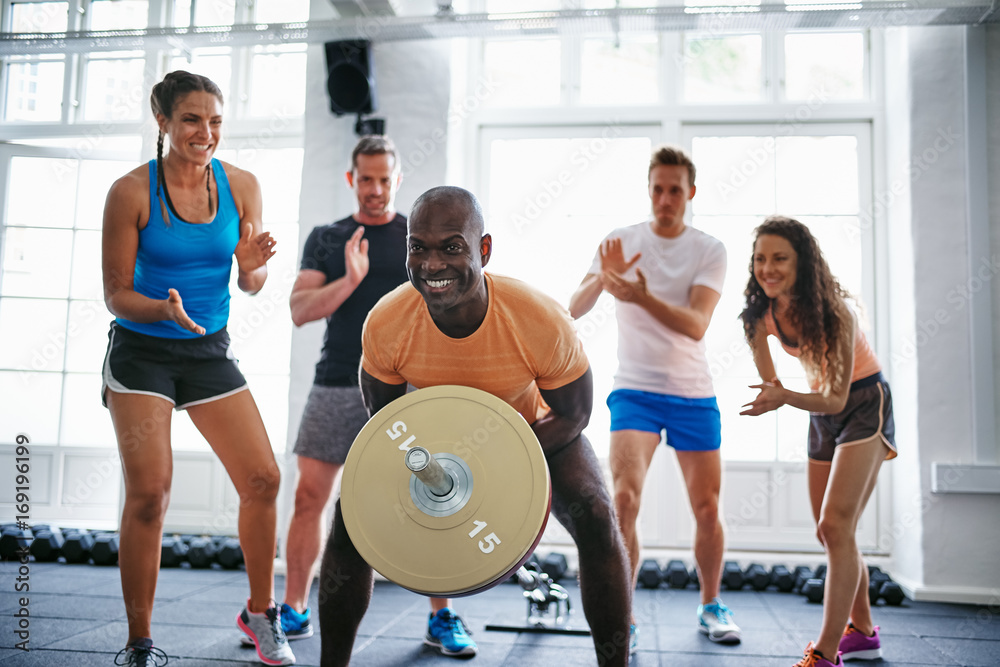 People cheering on their friend lifting weights in a gym Stock Photo ...