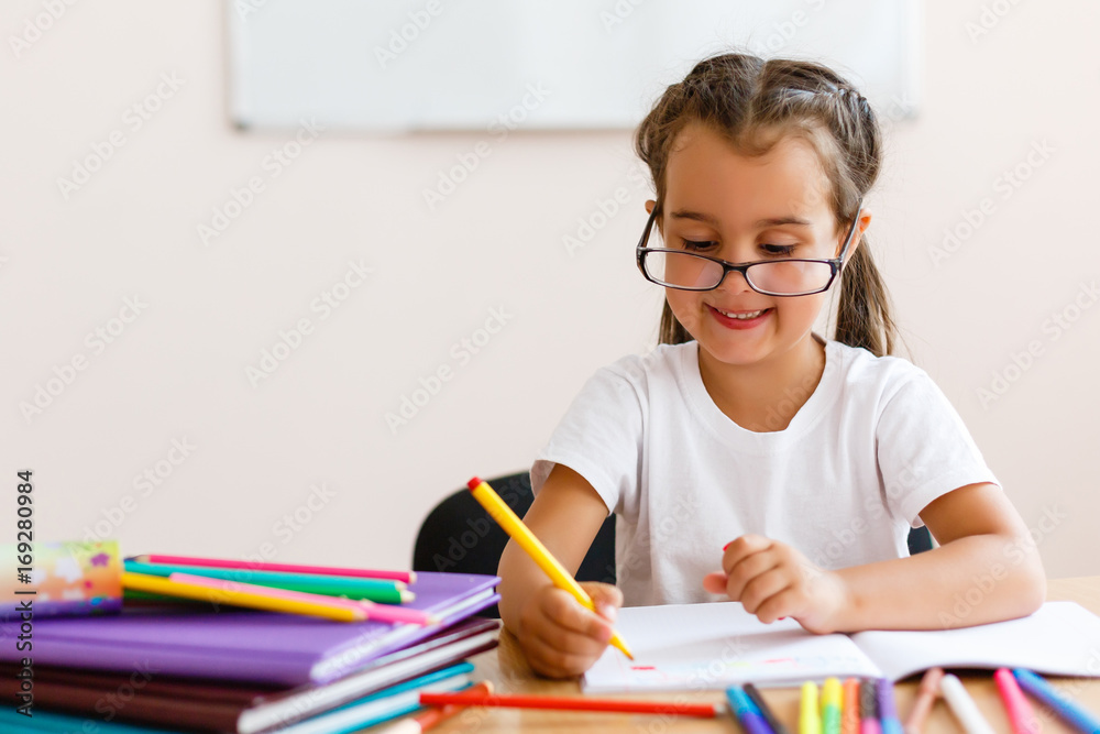 happy cute little girl doing school homework studying in living room at ...