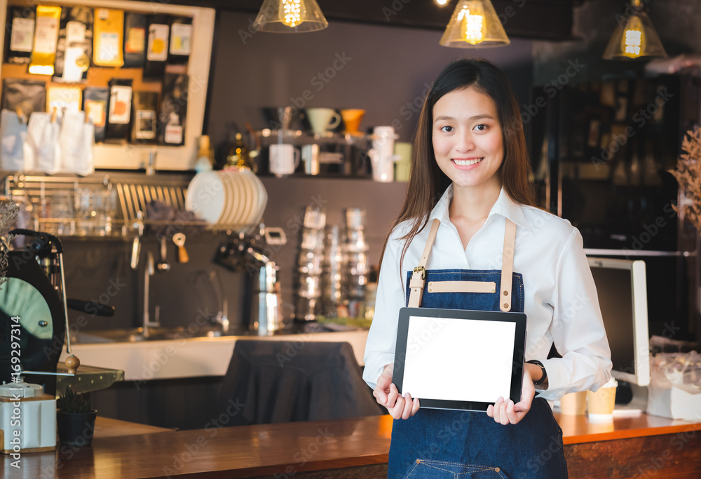 Smiling asian woman barista holding blank tablet compute in front of ...