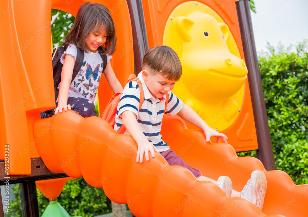 Two kids friends having fun to play together on children's slide at ...