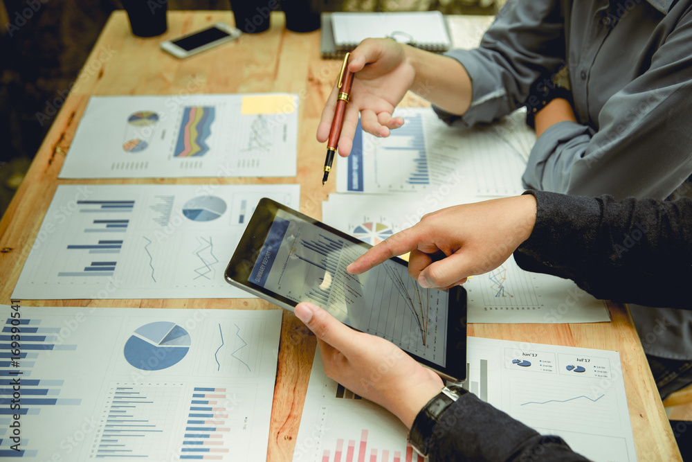 hand of businessman pointing tablet screen. There is his partner worker ...