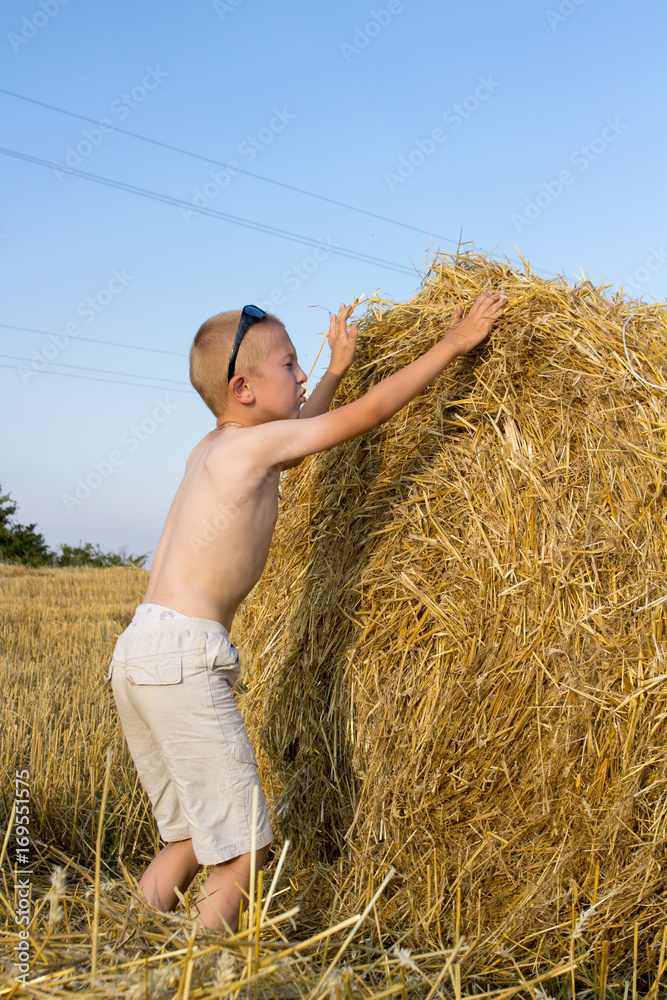Boy Climbing a Bale of Hay Stock Photo | Adobe Stock