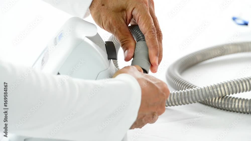 Man hands assembling patient tube to a cpap machine ,white background ...