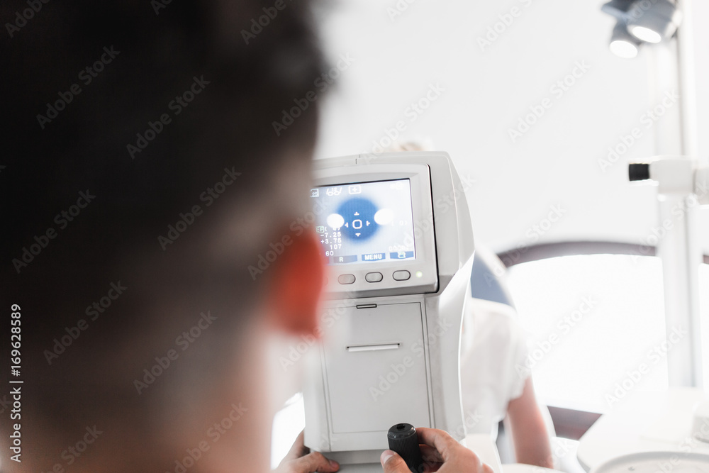 Male optometrist checking patient's vision at eye clinic. Medical ...