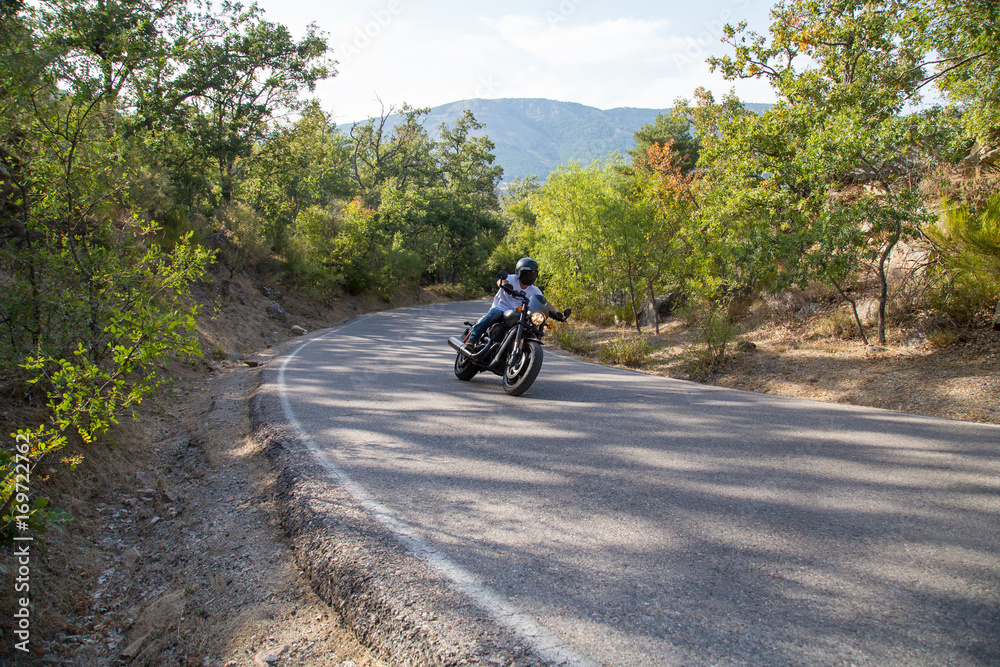 Young man riding a motorcycle on road turning in a curve in the ...