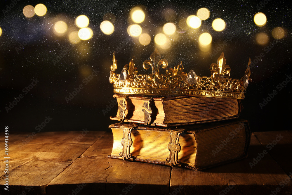 low key of beautiful queen/king crown on old books. vintage filtered ...