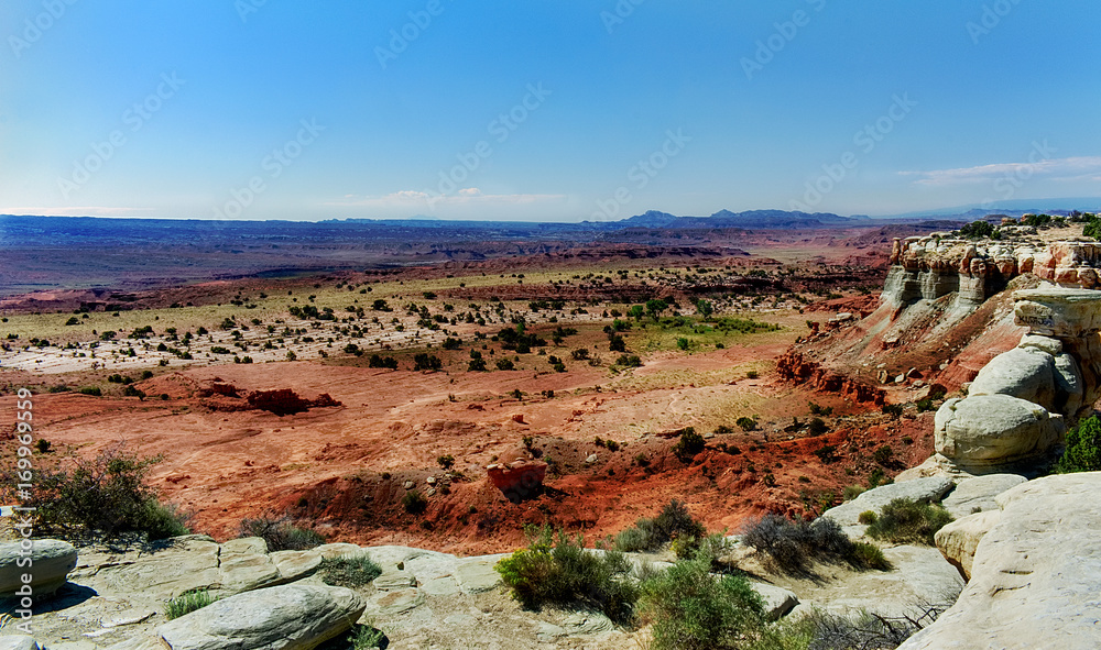 A vista of red and gray rocks with mountains in the background. The ...