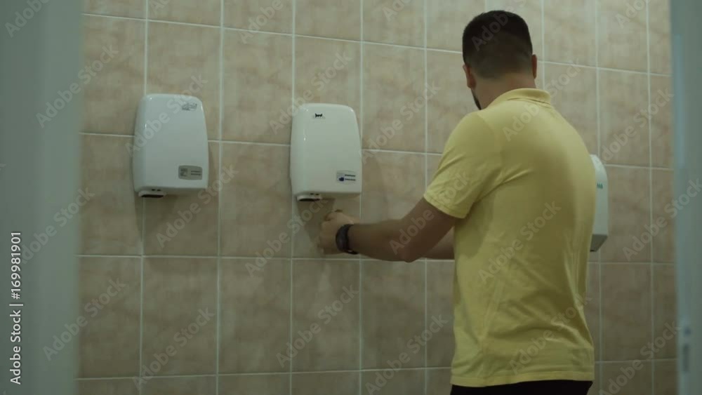 The man dries his hands and t-shirt in the toilet and using a hand ...
