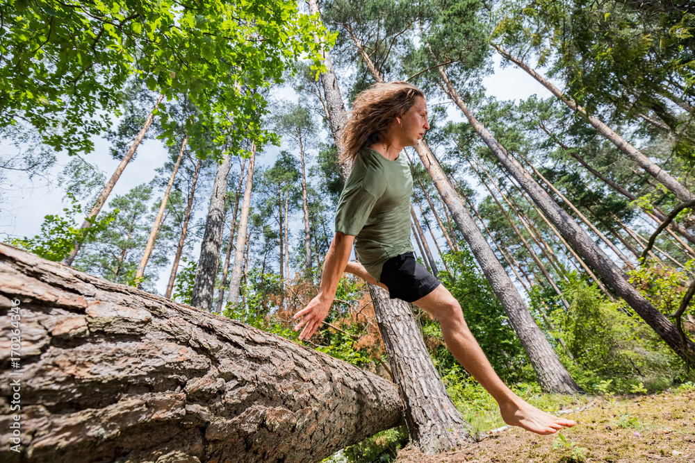 Young man jumping over a tree trunk in the forest. Stock Photo | Adobe ...
