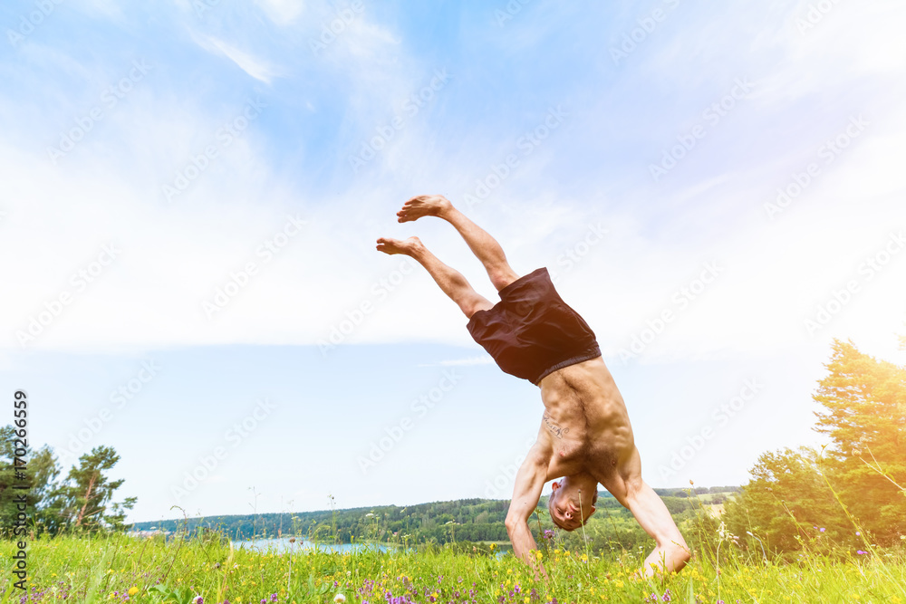 Young man doing a handstand on a filed. Stock Photo | Adobe Stock