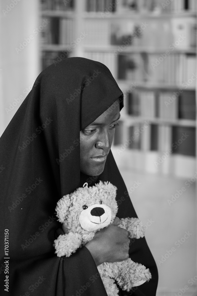 Portrait of a sad muslim girl wearing a hijab and holding her arms her ...