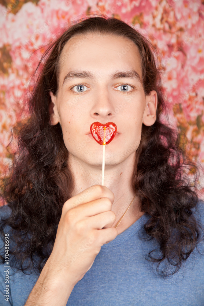 handsome romantic young man with red heart candy standing alone in the ...