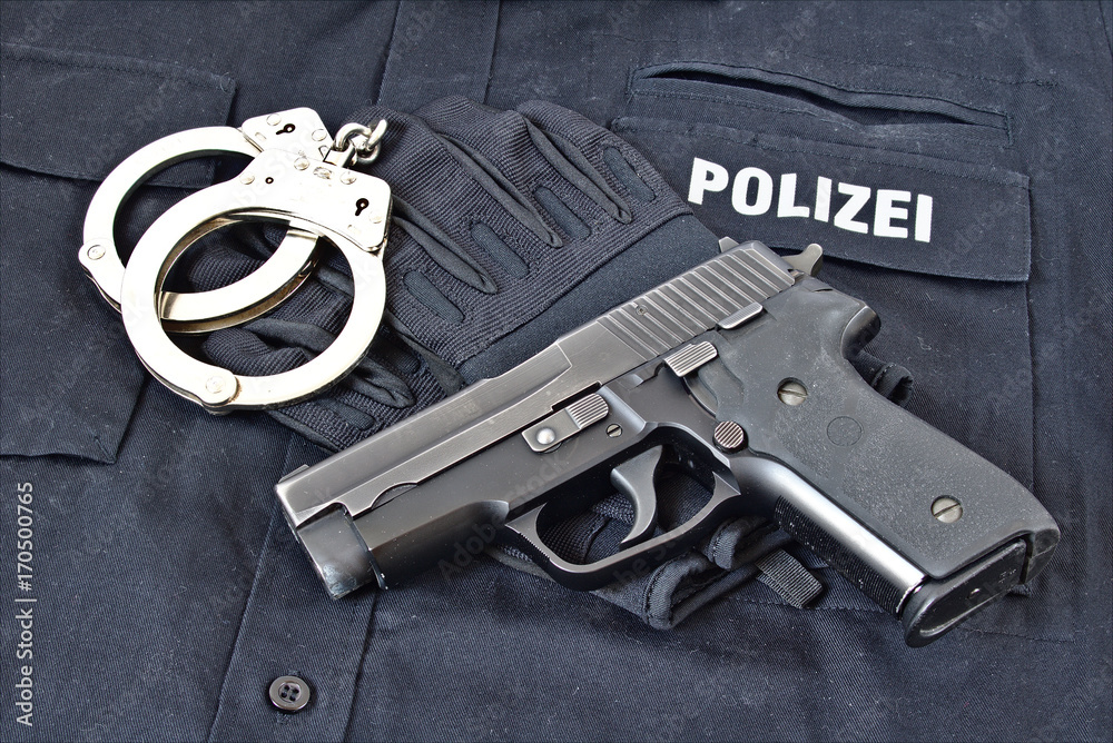 Pistole mit Handschellen und Handschuhen auf Uniformhemd mit dem ...