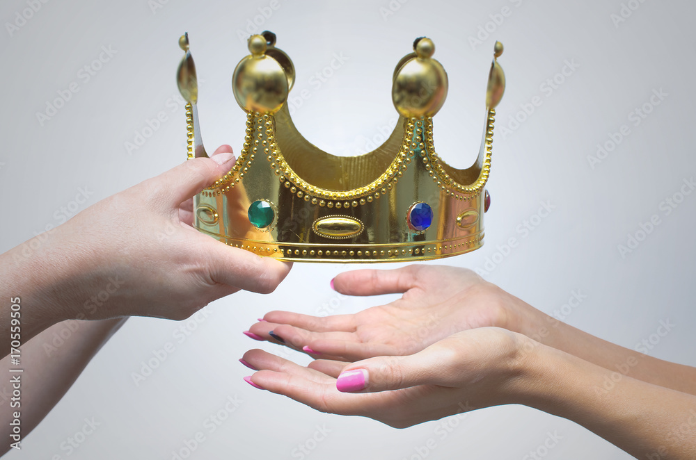 Hands gives the golden crown as symbol of power to another person ...