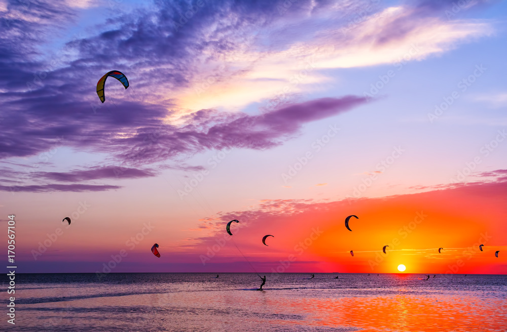 Kite-surfing against a beautiful sunset. Many silhouettes of kites in ...
