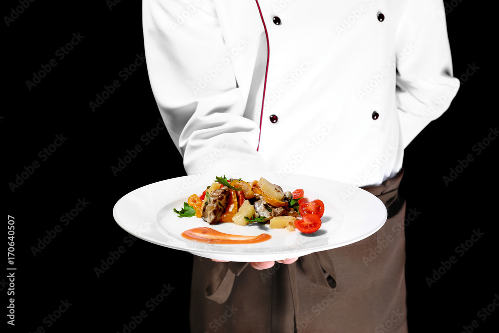 Chef holding freshly cooked dish on black background, closeup Stock ...