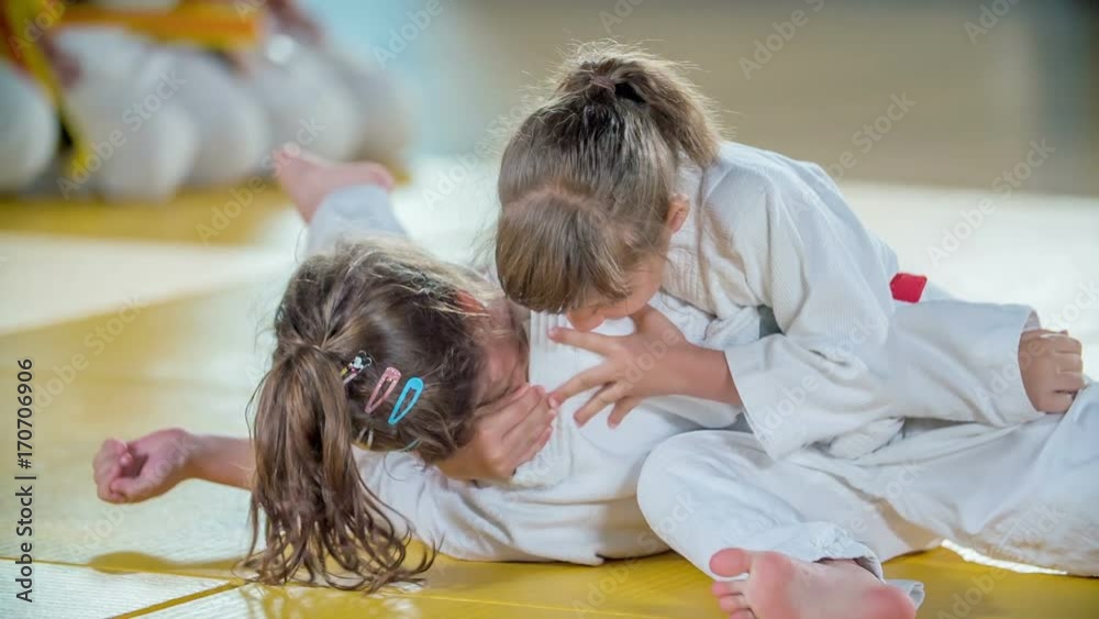 Two girls are fighting in judo practise and they are lying on the floor ...
