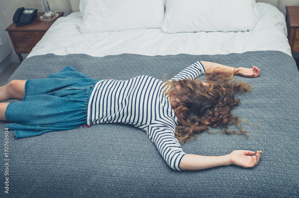 Exhausted woman on bed in hotel room Stock Photo | Adobe Stock