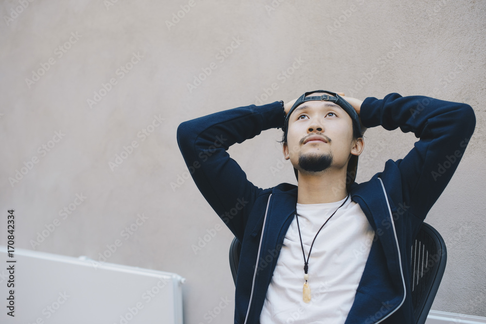 Thoughtful male computer programmer sitting with hands behind head ...