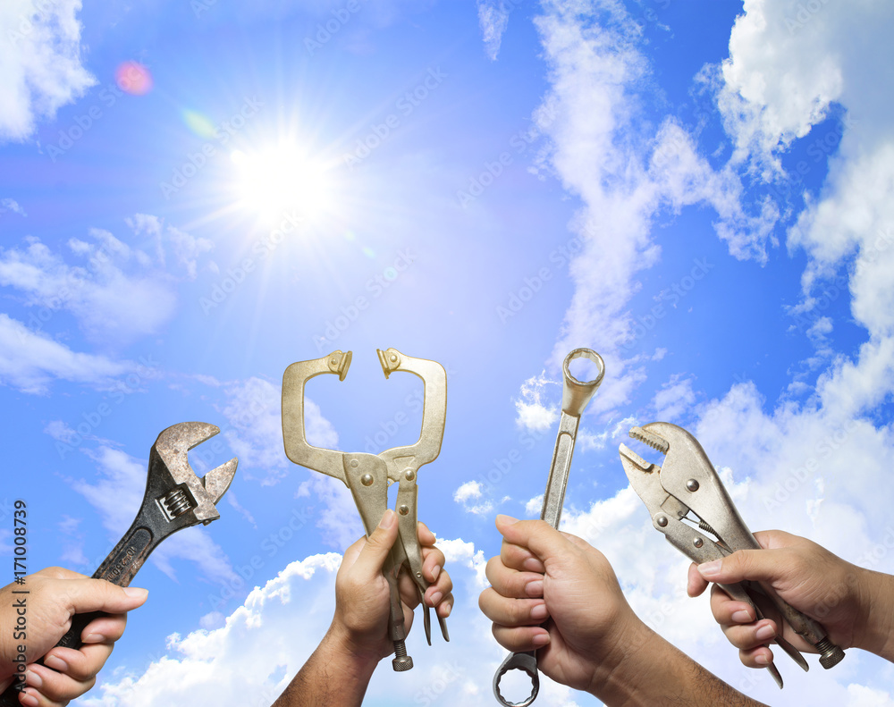 The hands of many mechanic holding instruments with blue sky background ...