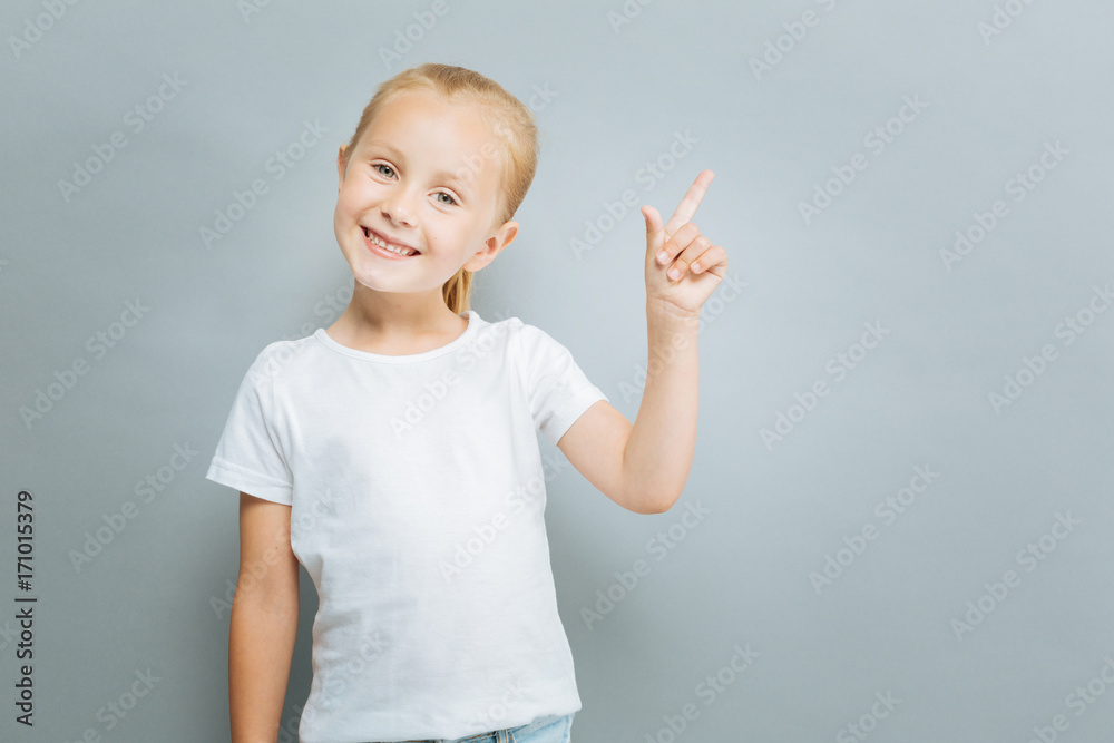 Delighted little child raising her forefinger Stock Photo | Adobe Stock