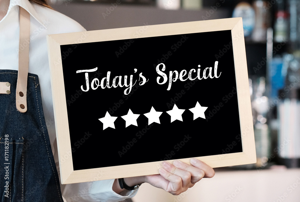 Hand holding Today's special and five start board sign over blur cafe ...
