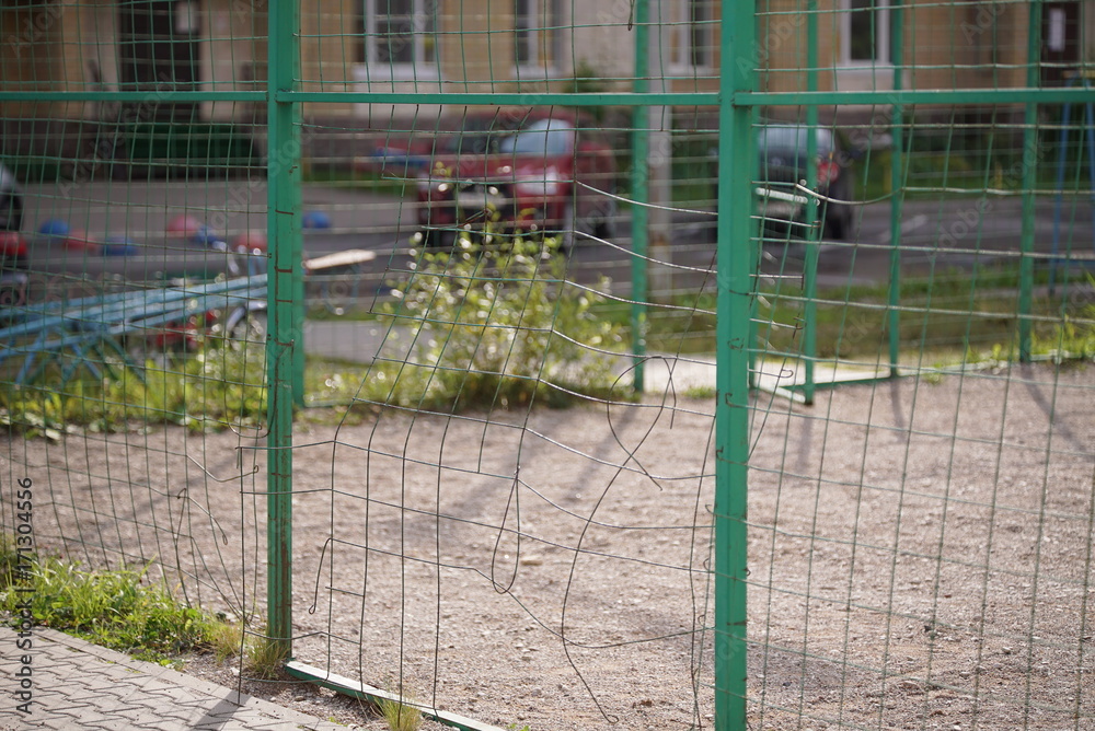Broken steel mesh of metal fence of a basketball court in residential ...