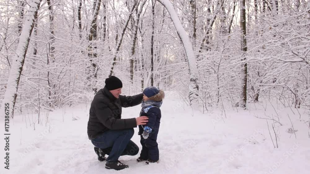 Caring young dad clears the snow from the head of his young son for a ...
