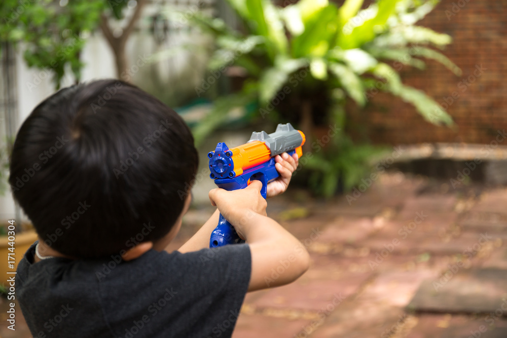 Little boy playing with a toy gun Stock Photo | Adobe Stock