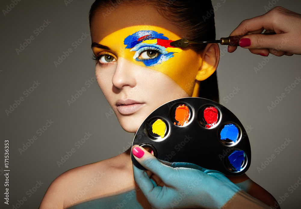 Makeup artist applies colorful makeup. Fashion model woman with colored ...