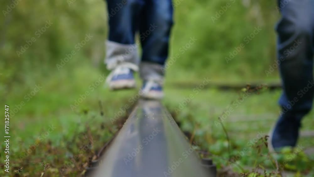 Closeup. The legs are on train tracks. Guy holds a child walking down ...