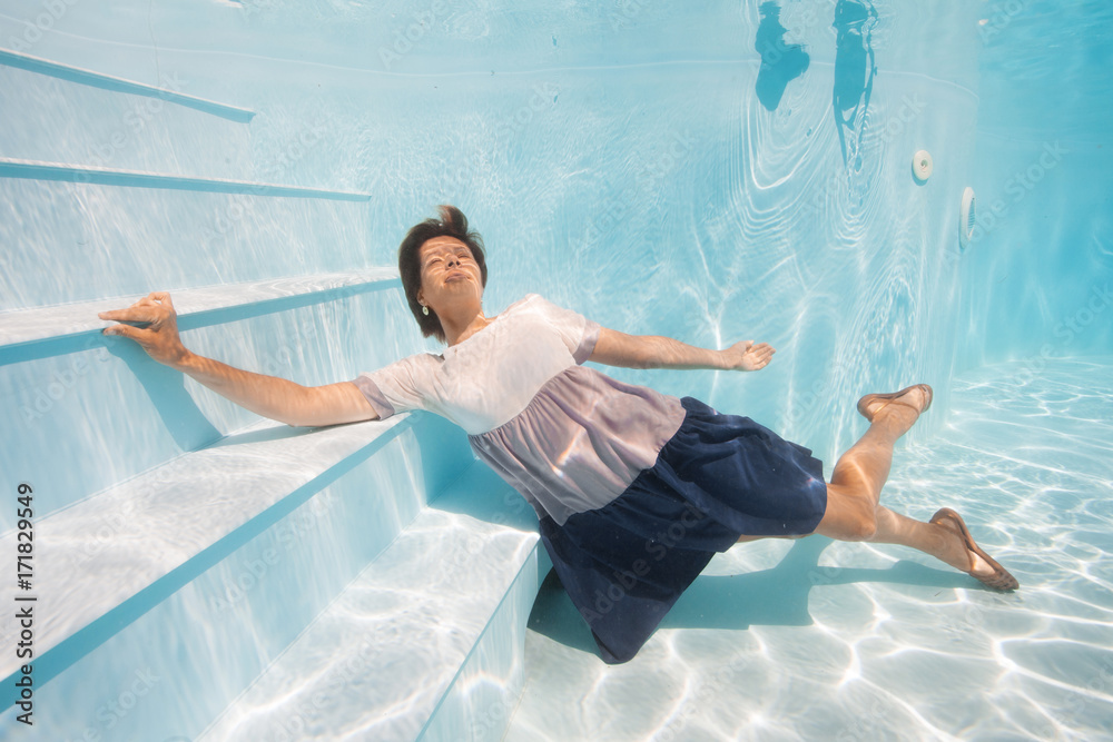 young woman in blue and white dress swim and dive underwater floating ...