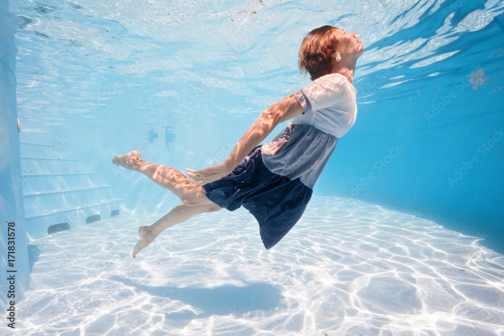 young woman in blue and white dress swim and dive underwater floating ...