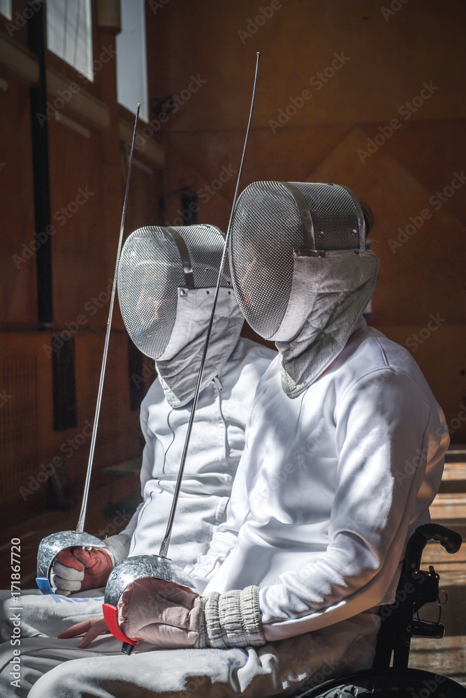 male fencer in wheelchair with safety mask of a face, holding rapier ...