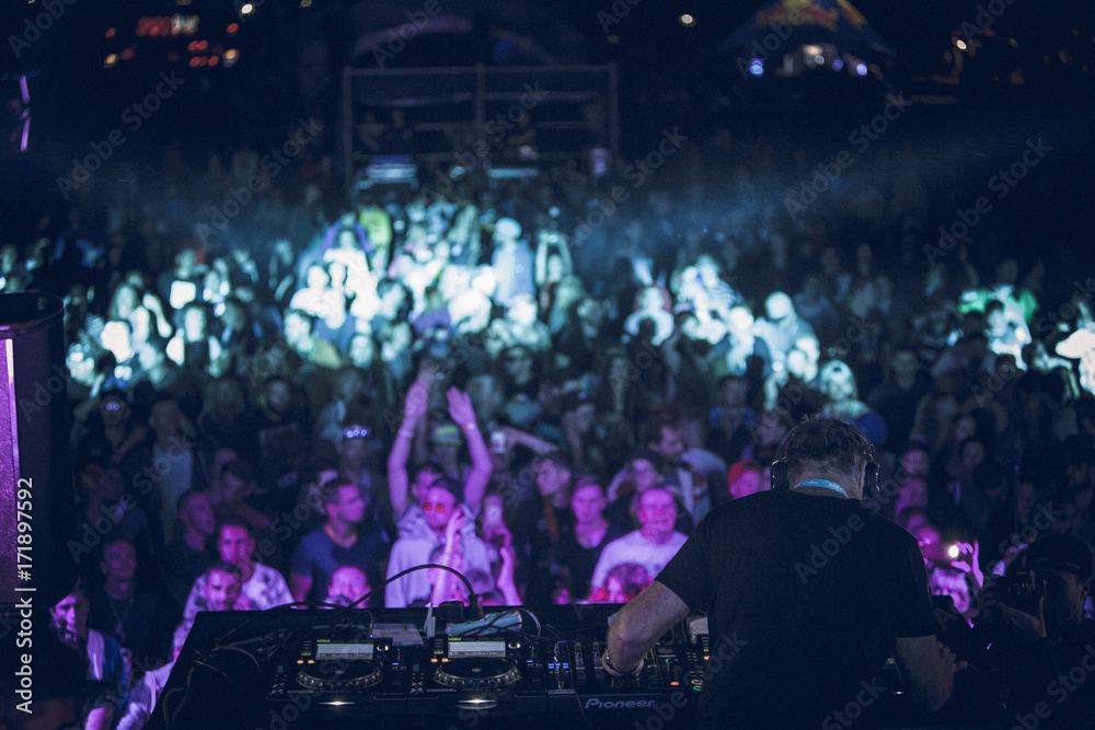 DJ with headphones at night club party under the colorful light and ...