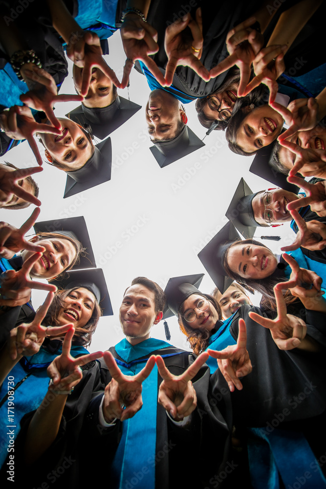 Group of graduates standing around and bend down to look at the camera ...