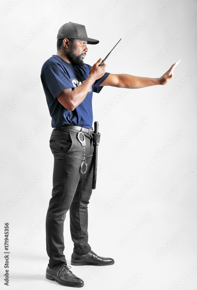 Male security guard showing stop gesture while using portable radio, on ...