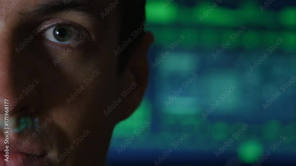 Portrait of Man programmer hacker with green code characters reflect on his face with a computer ...