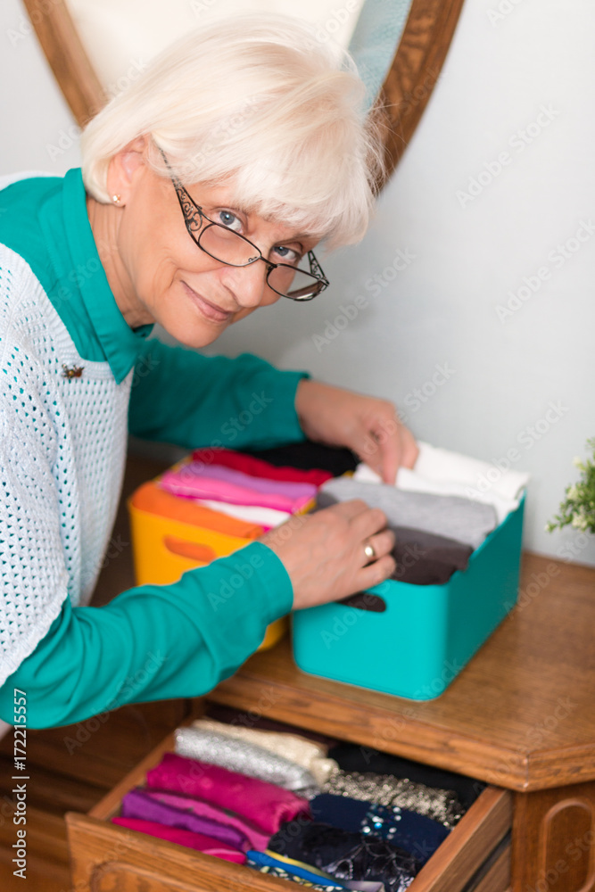 The European old blond woman brings wardrobe order, puts everything in ...