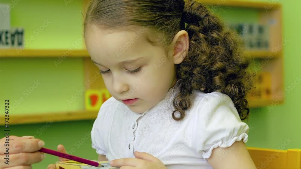A girl studying the lessons, a pretty baby girl does her schoolwork ...