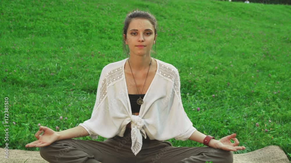 Young girl is doing the main pose of yoga called easy pose. She looks ...