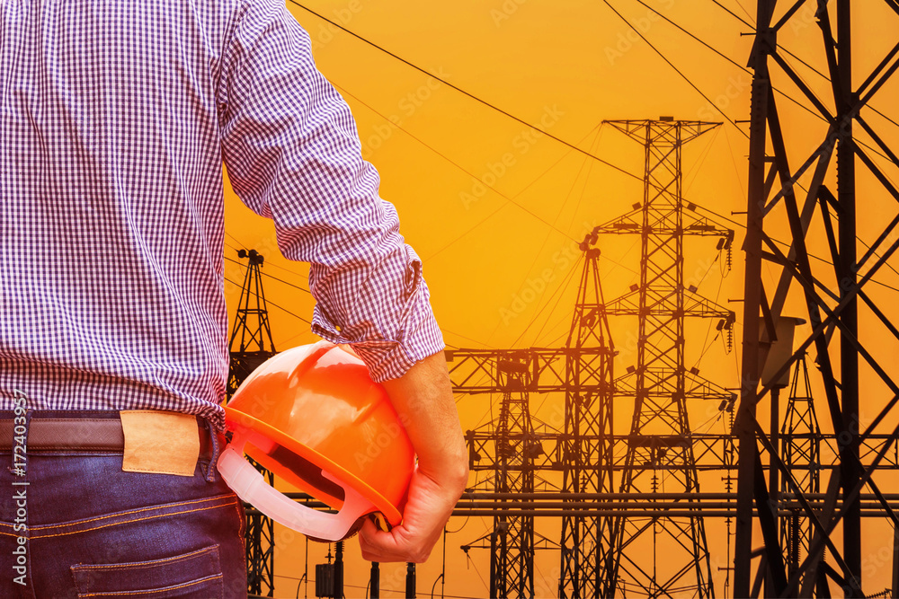 engineer holding yellow safety helmet with high voltage electric pylon ...