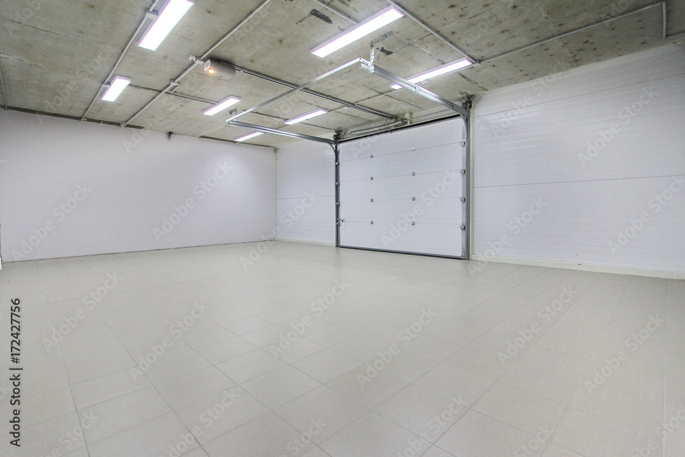 empty parking garage, warehouse interior with large white gates and ...